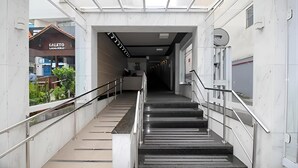 Escadaria interna moderna com corrimãos de metal e teto de vidro.
