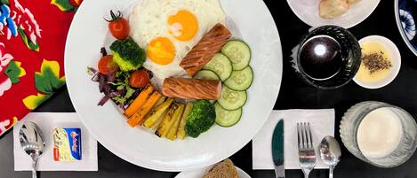 Prato de café da manhã com ovos, salmão, legumes e pão.