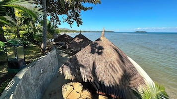 Uma praia com guarda-sóis de palha e vista clara para o mar.