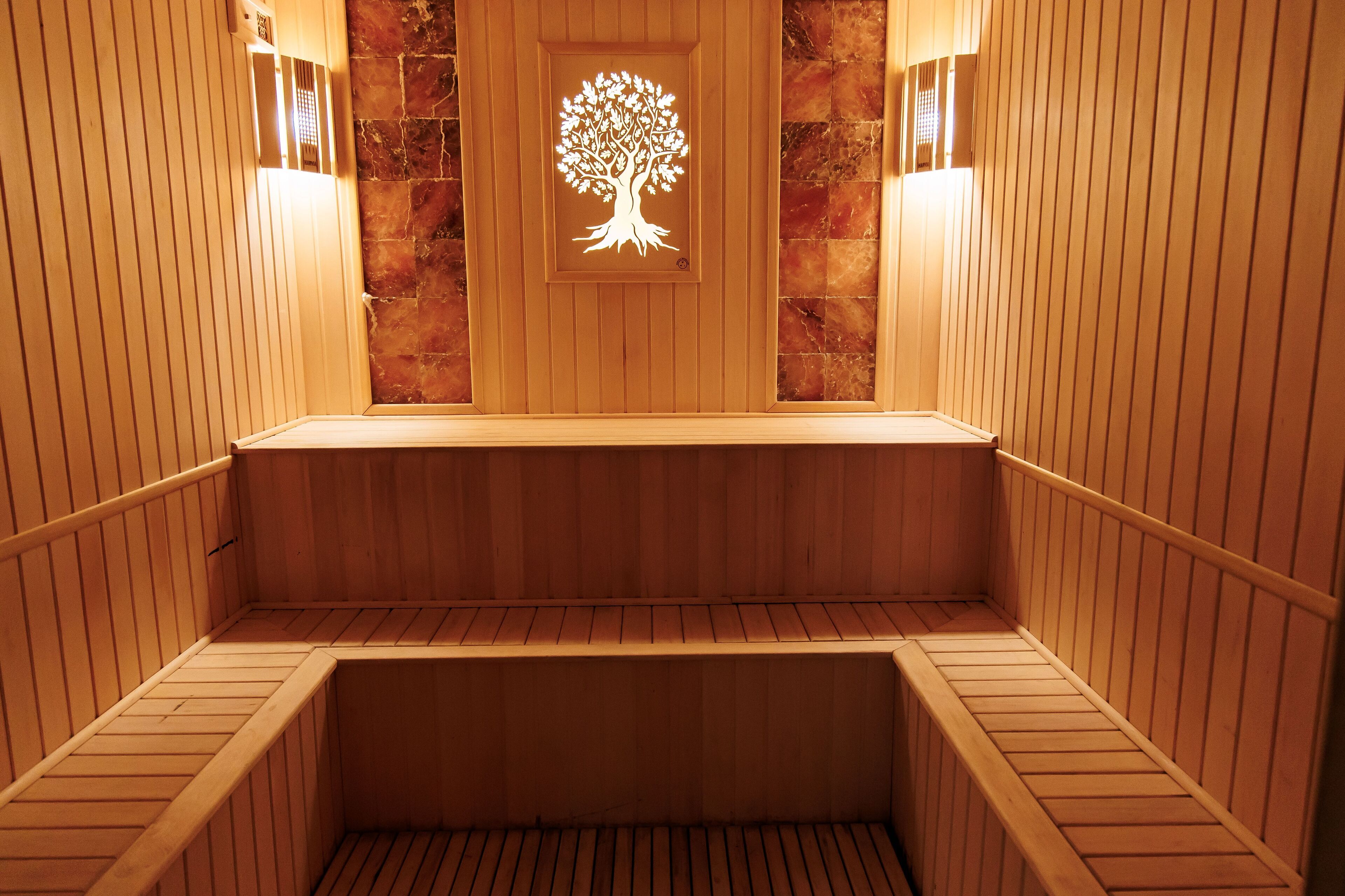Uma sauna com bancos de madeira e uma parede central com design de árvore.