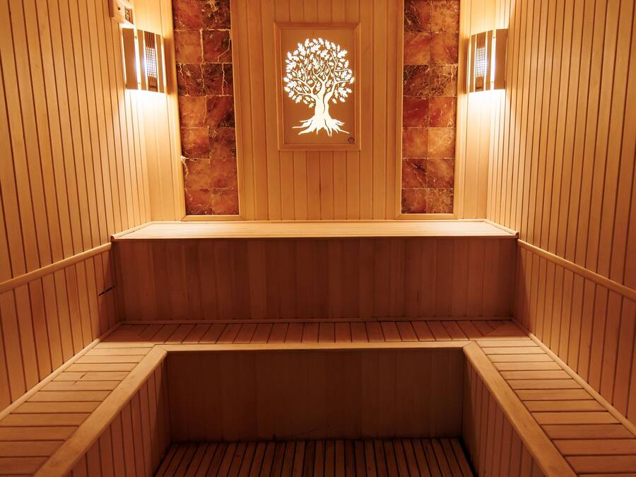 Uma sauna com bancos de madeira e uma parede central com design de árvore.