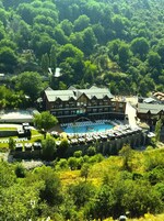 Resort com uma piscina grande, diversos quartos e paisagem exuberante ao redor.