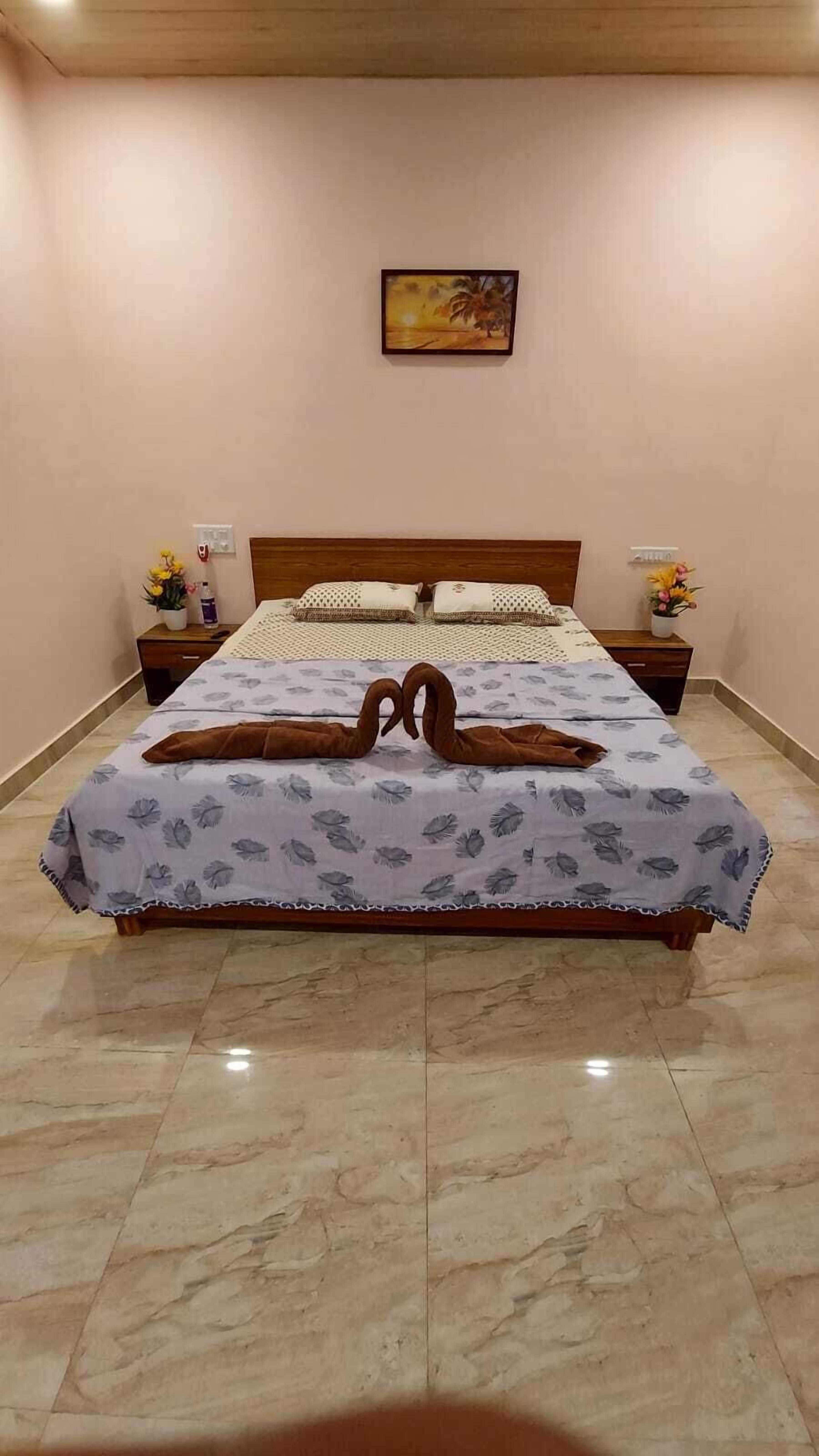 Quarto com cama, duas mesas de cabeceira, um quadro na parede e um edredom floral.