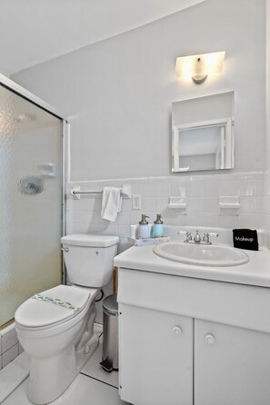 Uma casa de banho moderna com sanita, lavatório e chuveiro.