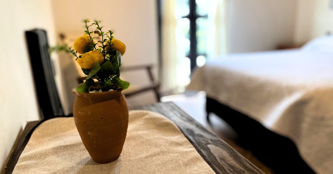 Uma cama com colcha branca e cabeceira de madeira.