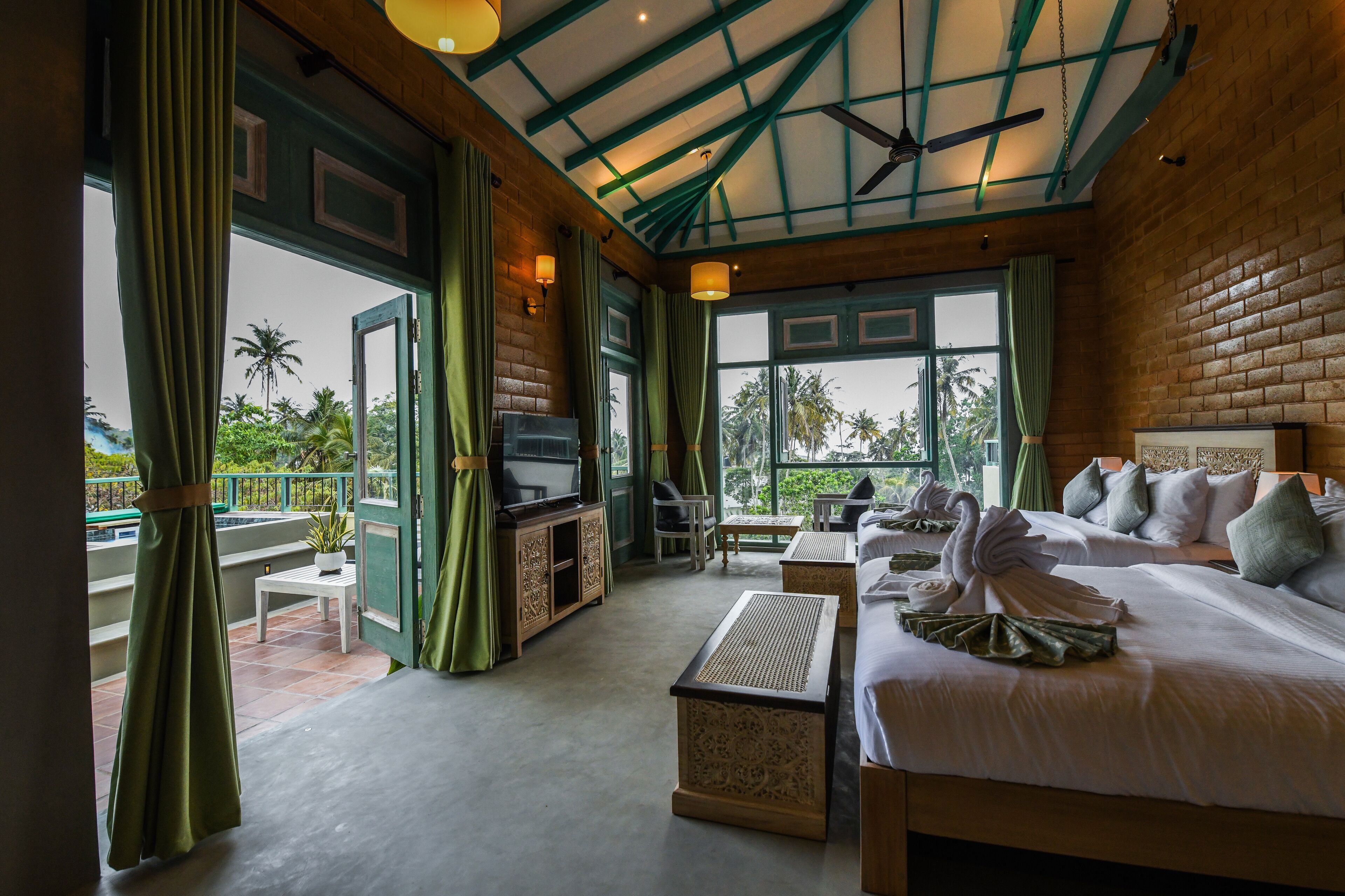Quarto de hotel com varanda, janelas amplas e uma cama com toalhas.