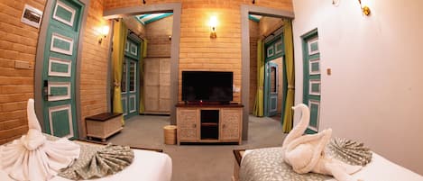 Quarto de hotel com duas camas, televisão e lareira.