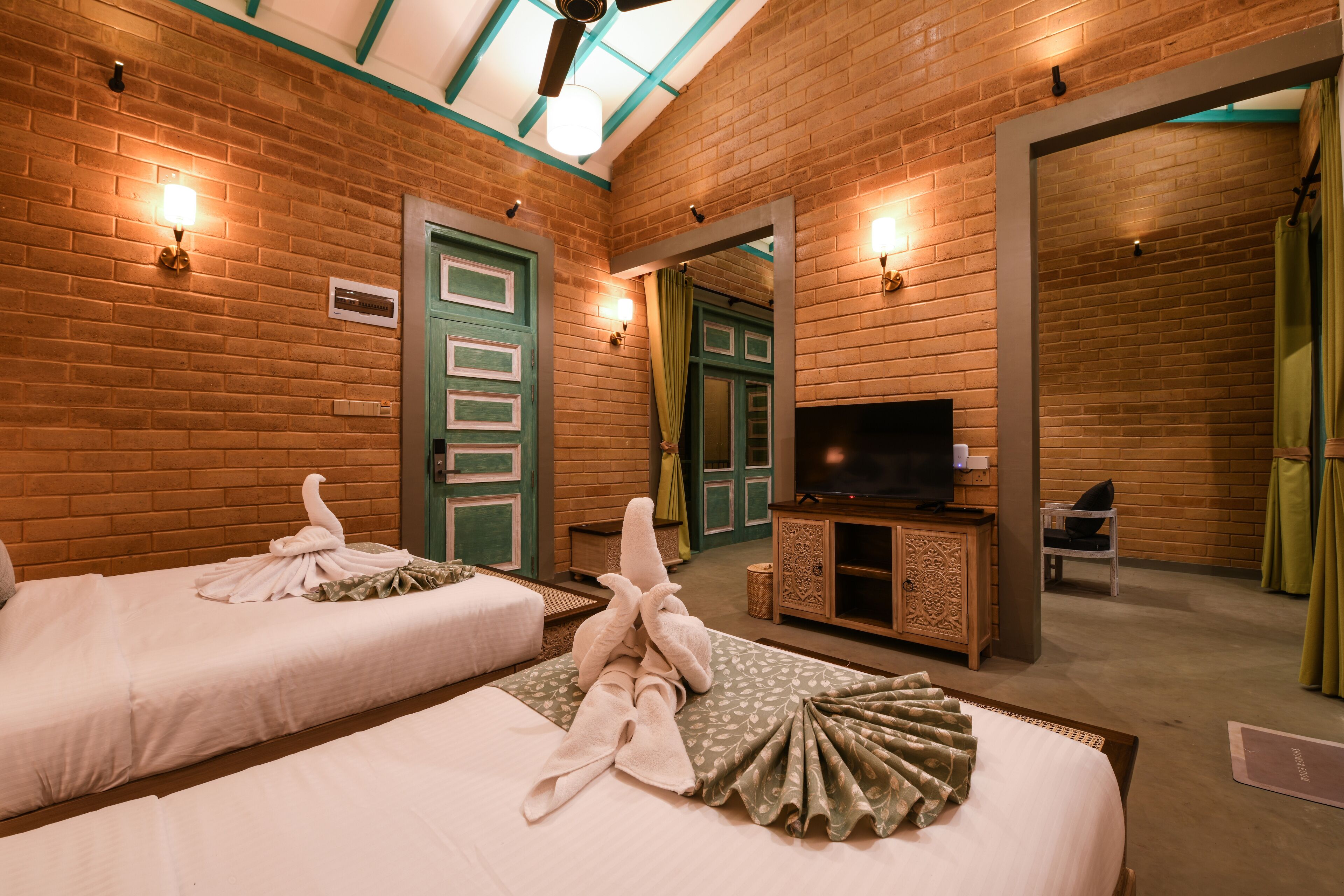 Quarto de hotel com duas camas, uma televisão e um espelho.