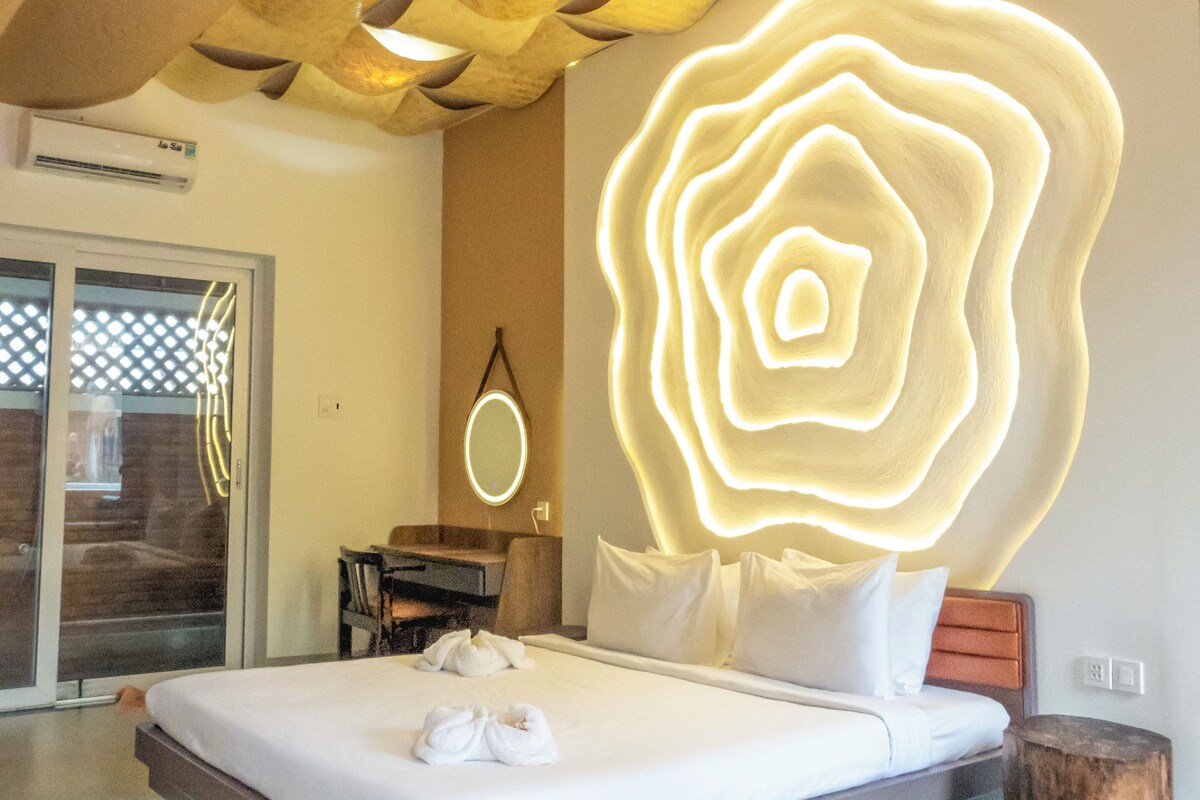 Quarto de hotel moderno com uma cama grande, um design de teto único e um candeeiro de parede.