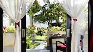 Área externa com vista para um jardim e um corpo d'água, com mesa e cadeiras.