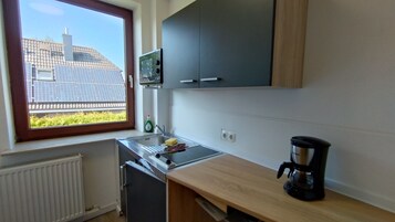 Apartamento superior, 2 quartos, sacada, vista parcial para o mar | Cozinha privada | Geladeira, micro-ondas, cooktop, torradeira