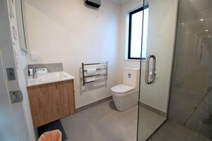 Um banheiro moderno com box de vidro, vaso sanitário e pia com armário de madeira.
