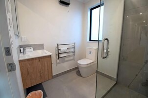 Um banheiro moderno com box de vidro, vaso sanitário e pia com armário de madeira.