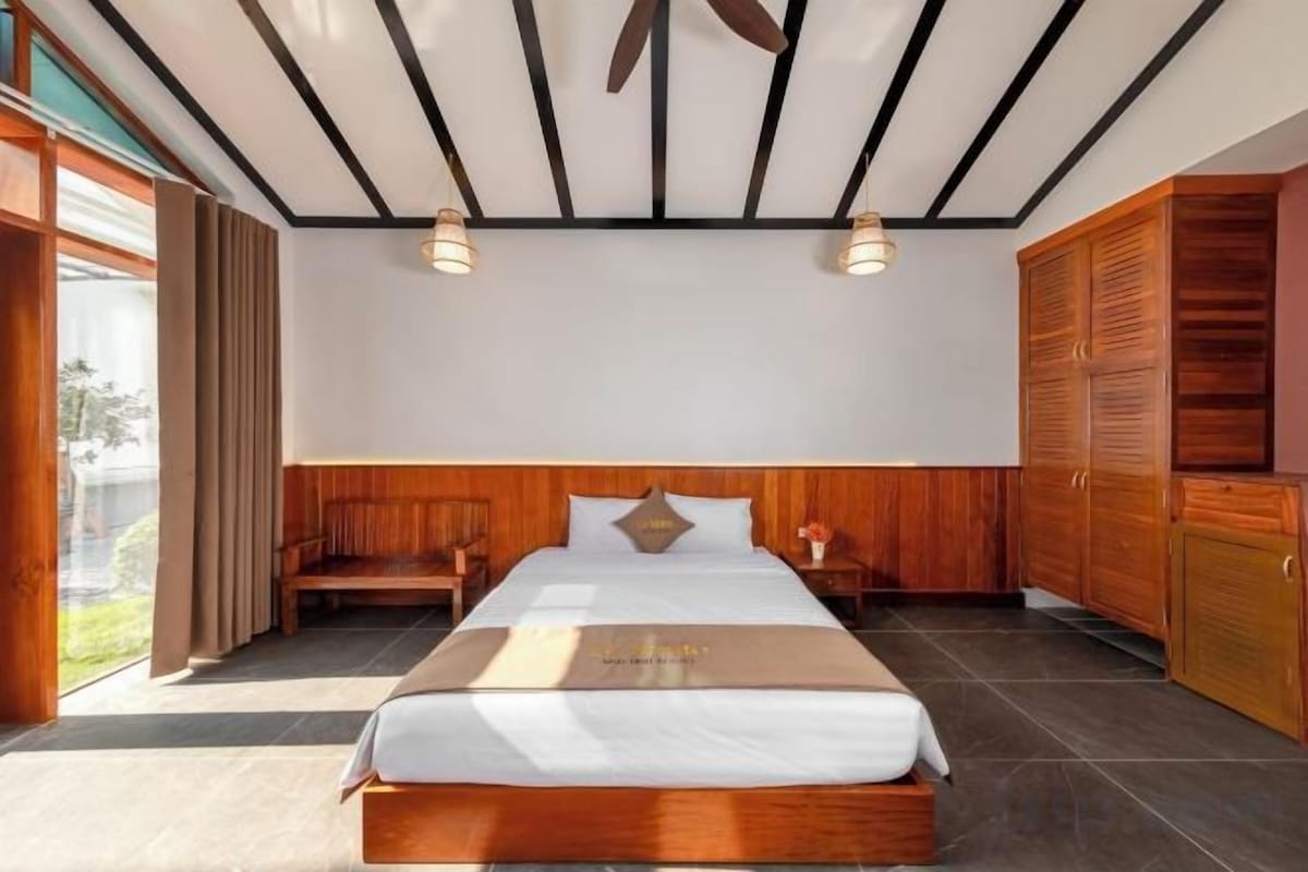 Quarto com uma cama grande, cabeceira de madeira e guarda-roupa.