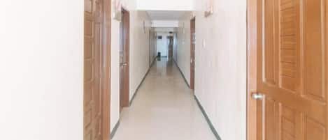 Um corredor com portas de madeira em ambos os lados, que leva a um quarto no final.