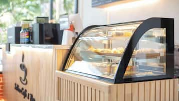 Vitrine de uma pastelaria com doces e uma máquina de café ao fundo.