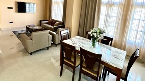 Uma sala de estar moderna com um sofá, cadeiras, uma mesa de jantar e uma televisão.