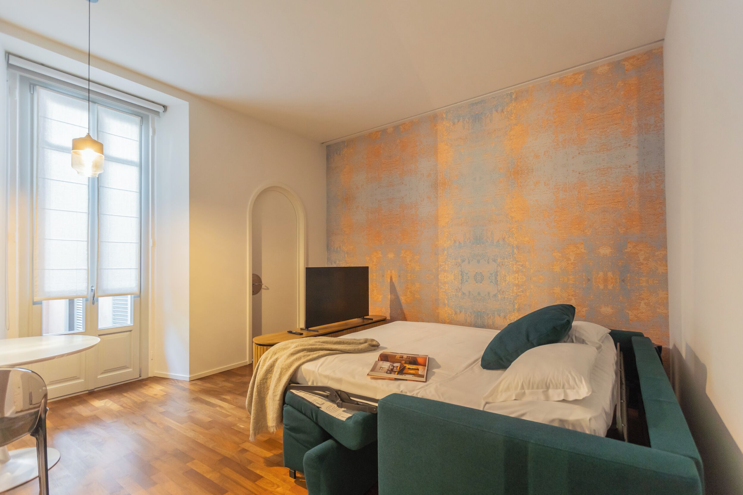 Quarto com cama, televisão, escrivaninha e cadeira.