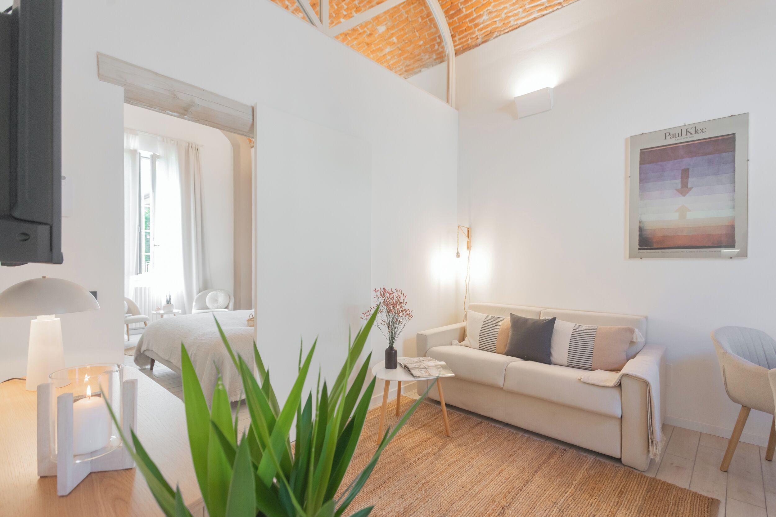 Uma sala de estar moderna com um sofá, uma mesa de centro, uma televisão e um quadro na parede.