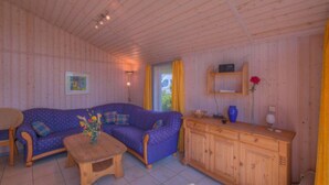 Um quarto acolhedor com um sofá azul, um armário de madeira e uma mesinha.