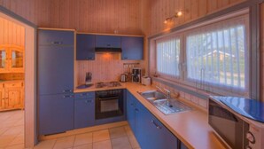 Cozinha compacta com armários de madeira, fogão, micro-ondas e uma janela grande que proporciona iluminação natural.