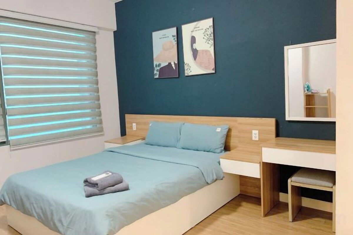Quarto com cama, mesa de cabeceira, escrivaninha e espelho.