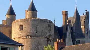 Um castelo de pedra histórico com várias torres e uma torre central redonda, rodeado por edifícios tradicionais com telhados inclinados.