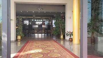 Um saguão de hotel com carpete estampado, balcão de recepção e plantas em vasos.