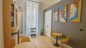 Uma sala de estar moderna com área de jantar, piso de madeira e uma janela grande com cortinas leves.