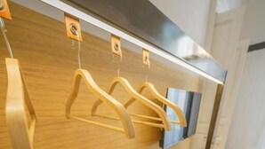 Uma cozinha moderna com móveis de madeira, um laptop sobre uma mesa e um cabideiro.