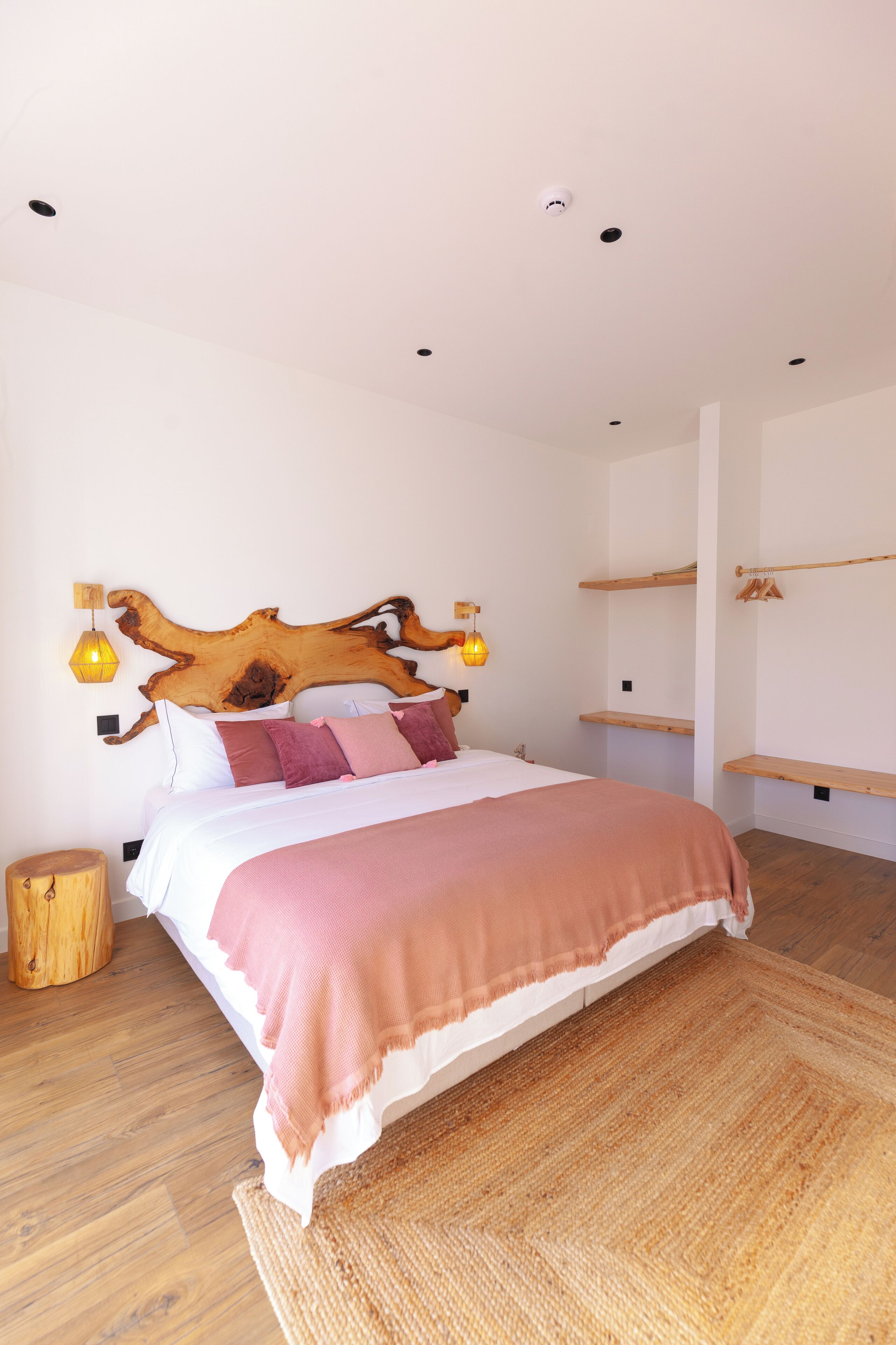Quarto com cama grande, cabeceira de madeira e estantes embutidas.