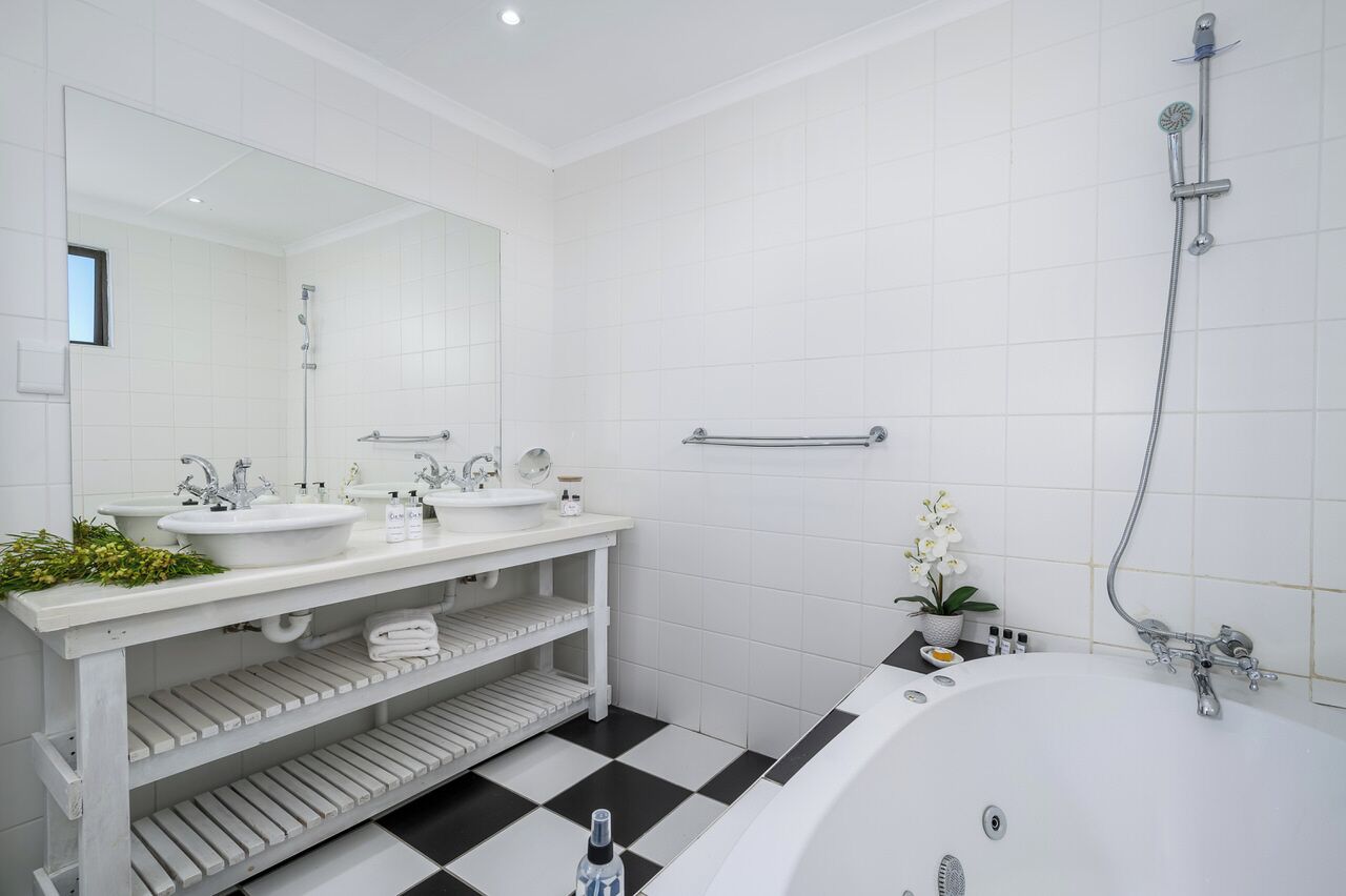Uma casa de banho moderna com uma banheira grande, duas pias, um espelho e um chuveiro.
