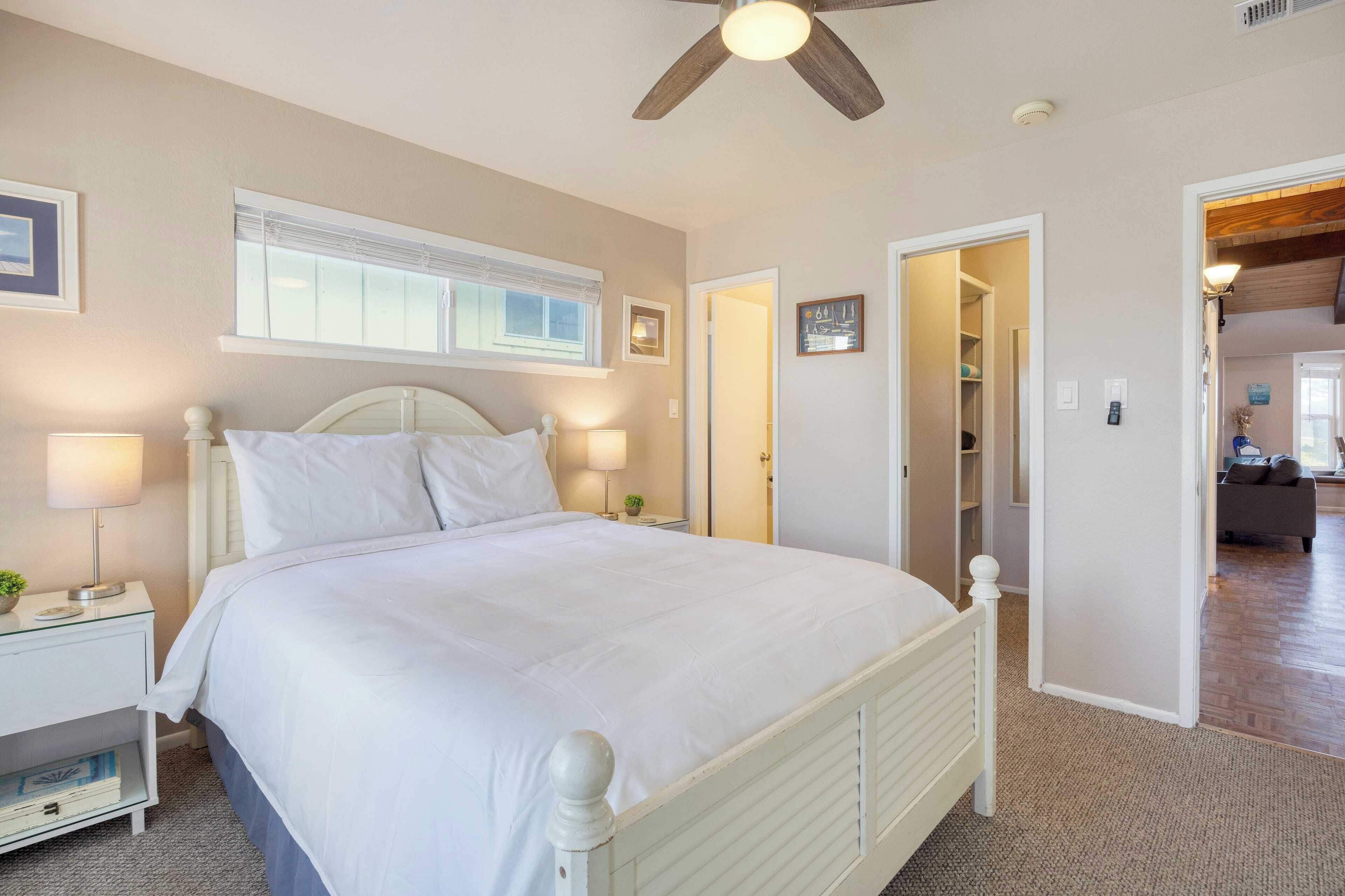 Quarto com cama, mesas de cabeceira, ventilador de teto e janela.