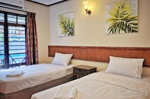 Quarto de hotel com duas camas, cabeceira de madeira, mesa de cabeceira e janela com cortinas.