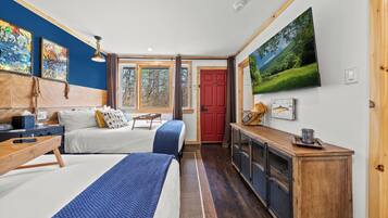 Quarto de hotel moderno com cama, mesa de cabeceira e uma janela grande.