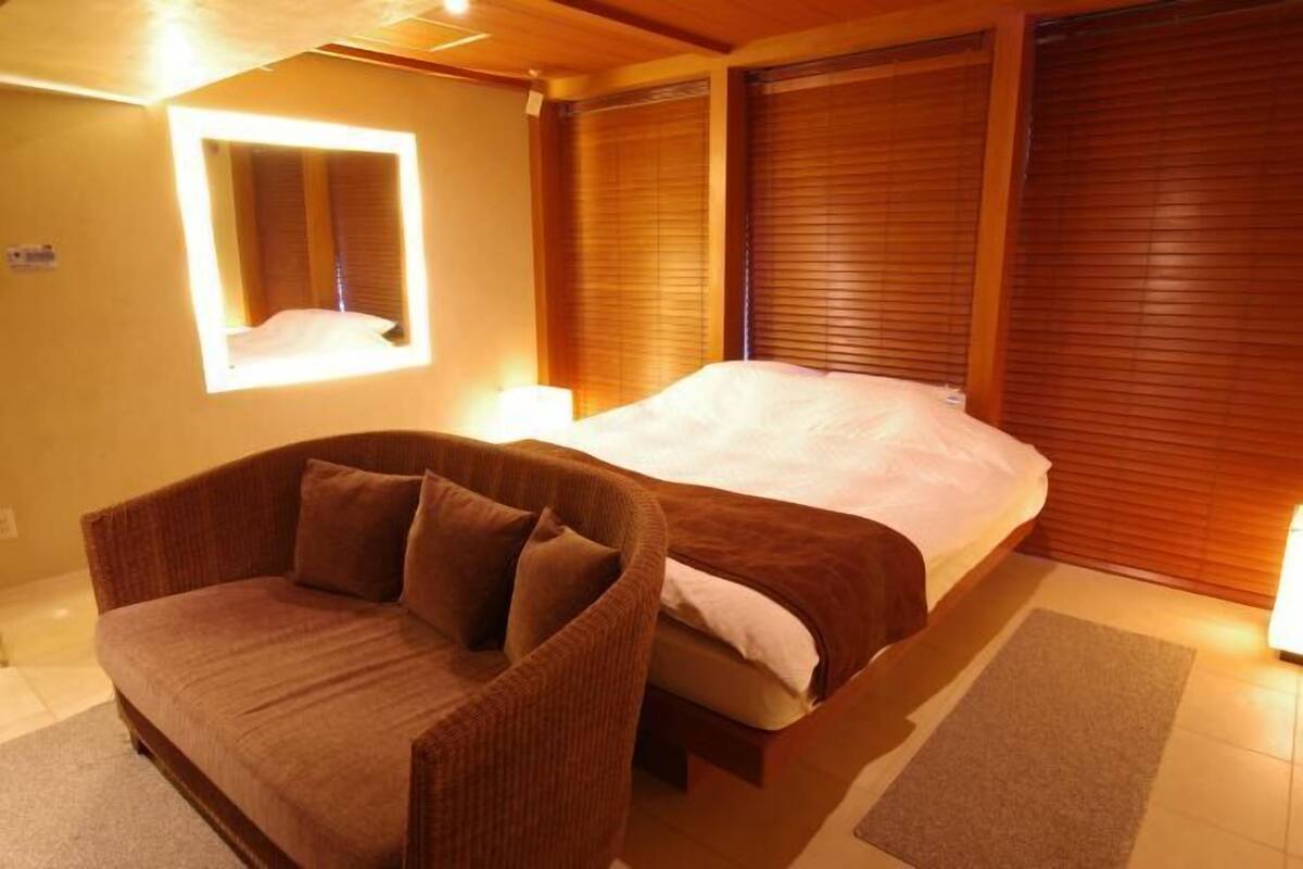 Quarto com cama, sofá, janela e porta de madeira.