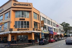Um edifício de vários andares com um letreiro chamativo da 'Continental', lojas e carros estacionados na rua.