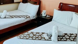 Duas camas de solteiro com cabeceiras de madeira, roupa de cama branca e toalhas.