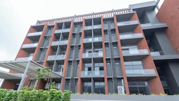 Um edifício de vários andares com design arquitetônico moderno, combinando fachadas de tijolo e vidro, e uma série de varandas.