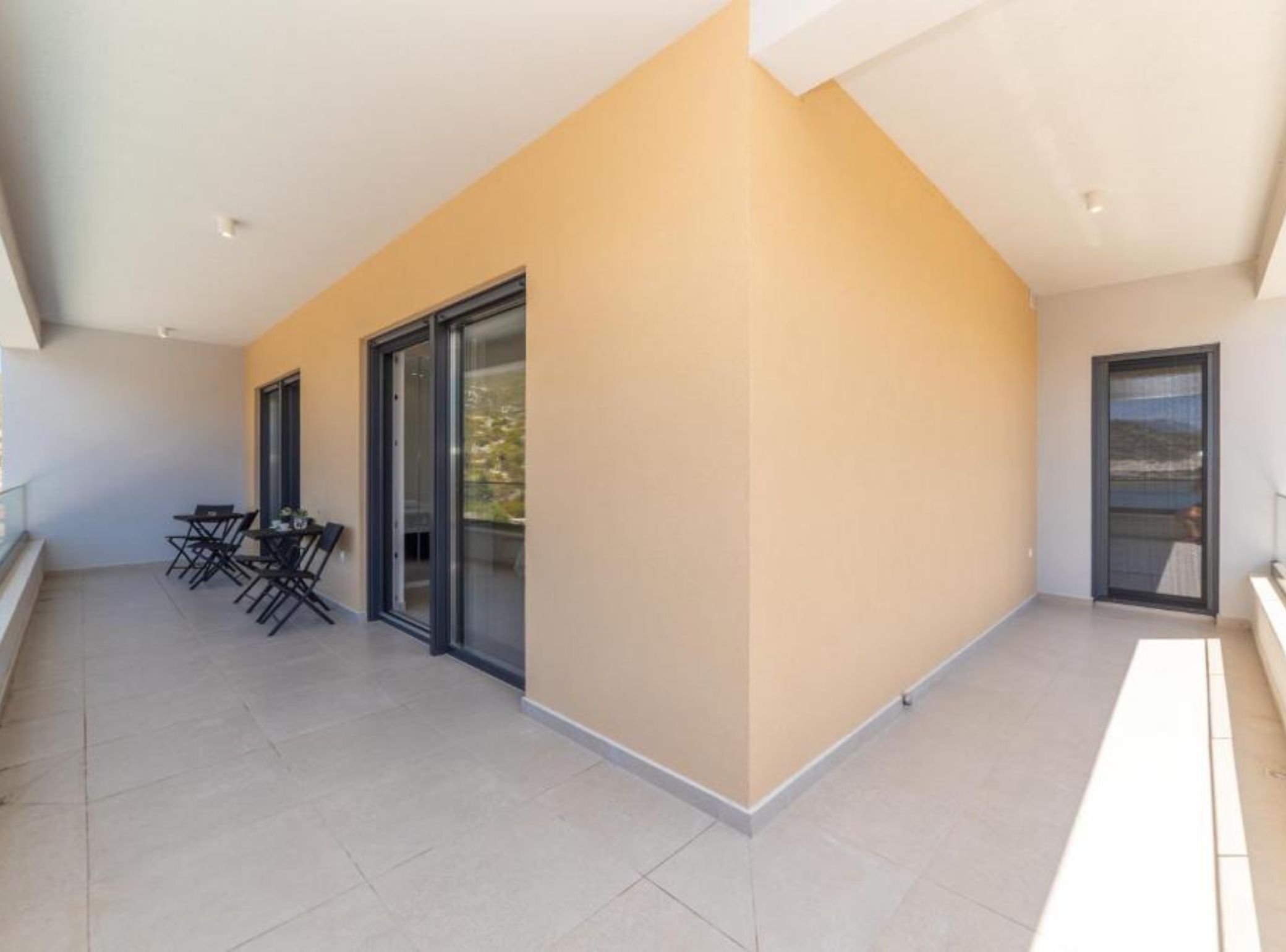 Um apartamento moderno com varanda, área de jantar e porta de vidro deslizante.
