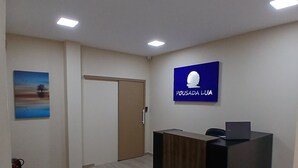 Uma área de recepção com uma mesa de madeira, uma placa azul e um quadro na parede.