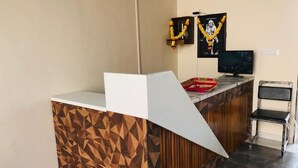 Uma receção com painel de madeira de design geométrico, uma televisão e um quadro na parede.