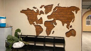 Um mural de um mapa mundi numa parede, com um banco na frente.