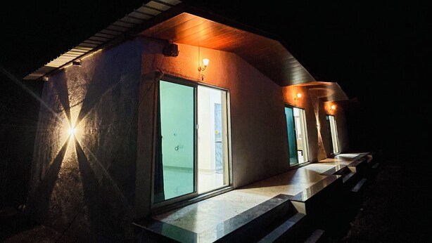 Uma casa moderna com uma grande porta de vidro, um pequeno alpendre e um lustre sobre a porta.
