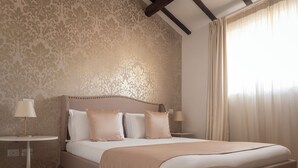 Quarto com cama, duas mesas de cabeceira, abajur e janela com cortinas.