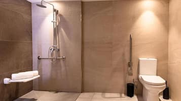Uma casa de banho moderna com chuveiro, sanita e porta-toalhas.