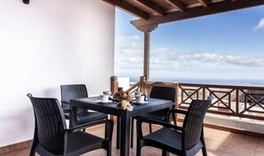 Varanda com mesa posta para dois, com vista para o mar.