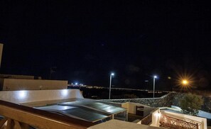 Terraço no telhado com vista para a paisagem urbana à noite.