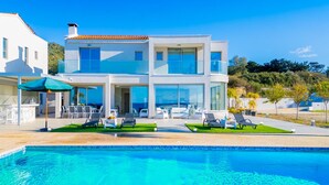 Uma casa moderna de dois andares com piscina, área de estar ao ar livre e vista ampla do céu.