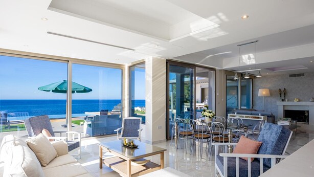 Uma sala de estar moderna com uma grande porta de vidro que dá para uma varanda com vista para o mar.